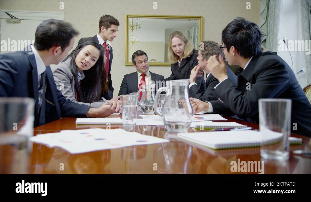 Diverse group of business people are seated around a conference table ...