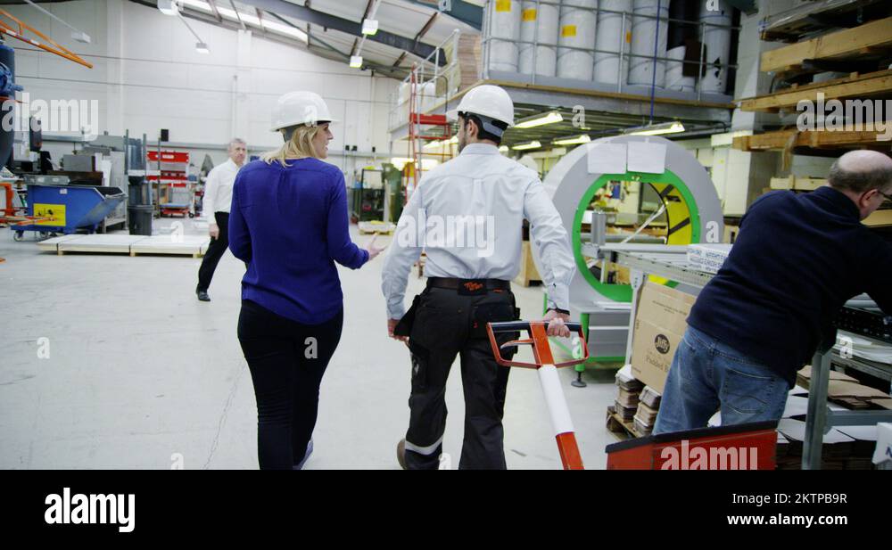 4K Industrial workers talking as they walk through busy factory ...