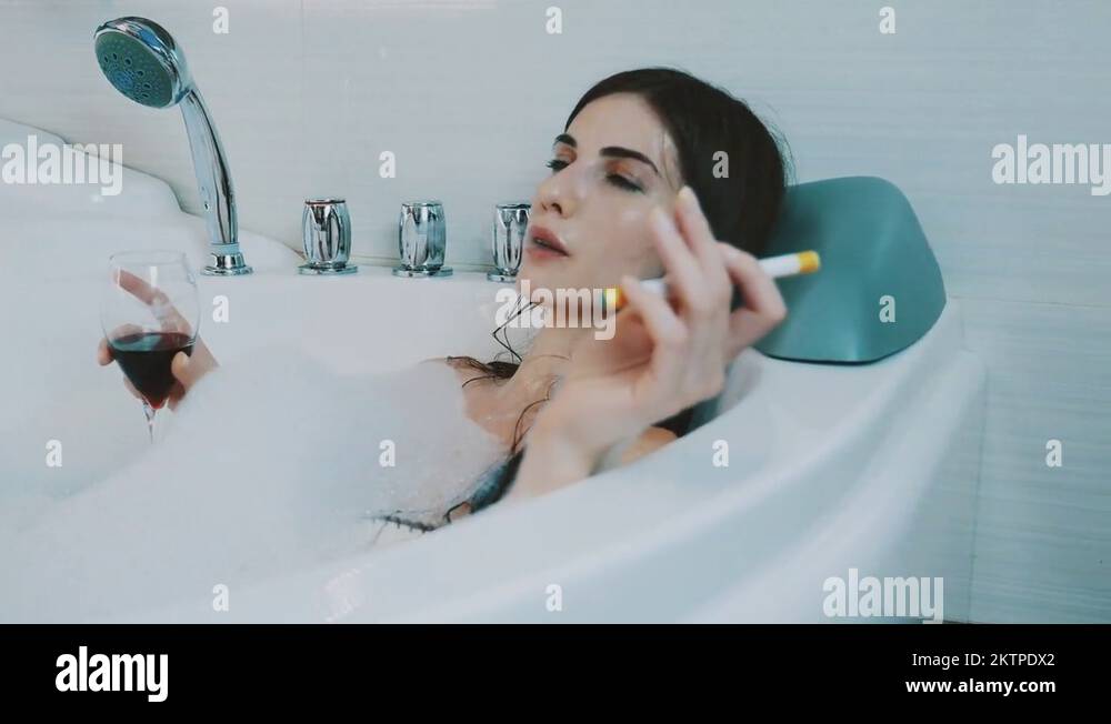 Girl drink red wine in bath full of foam. Smoking electronic cigarette. Resting Stock Video ...