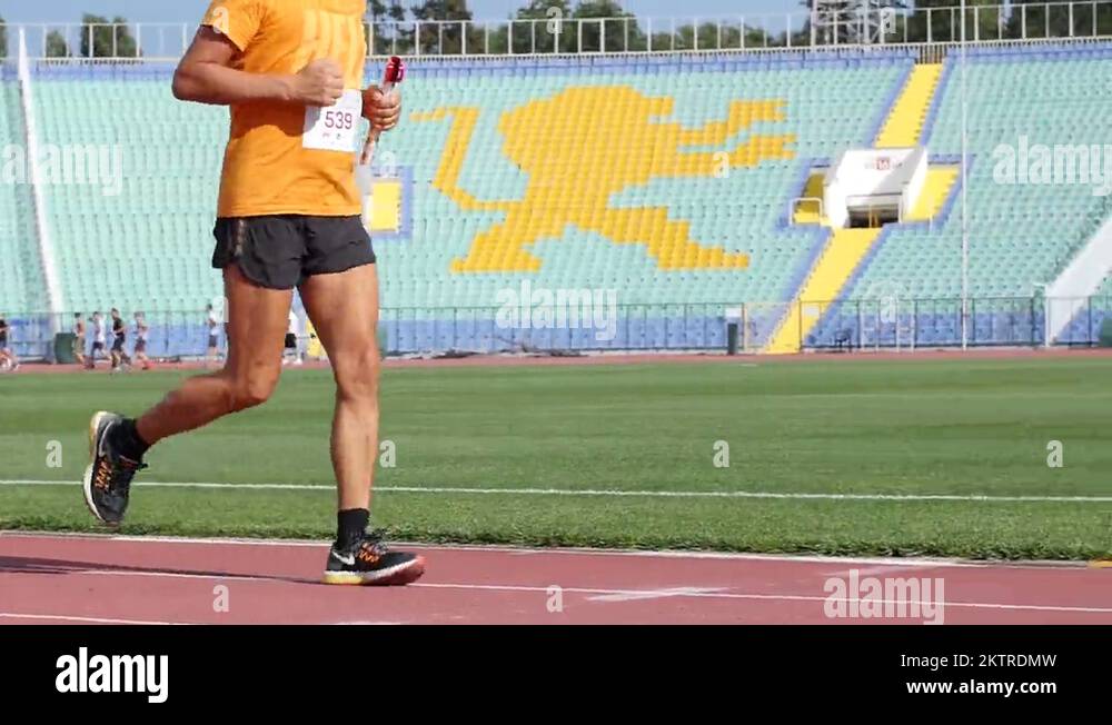 Strong healthy body legs man run on running stadium tracks during relay ...