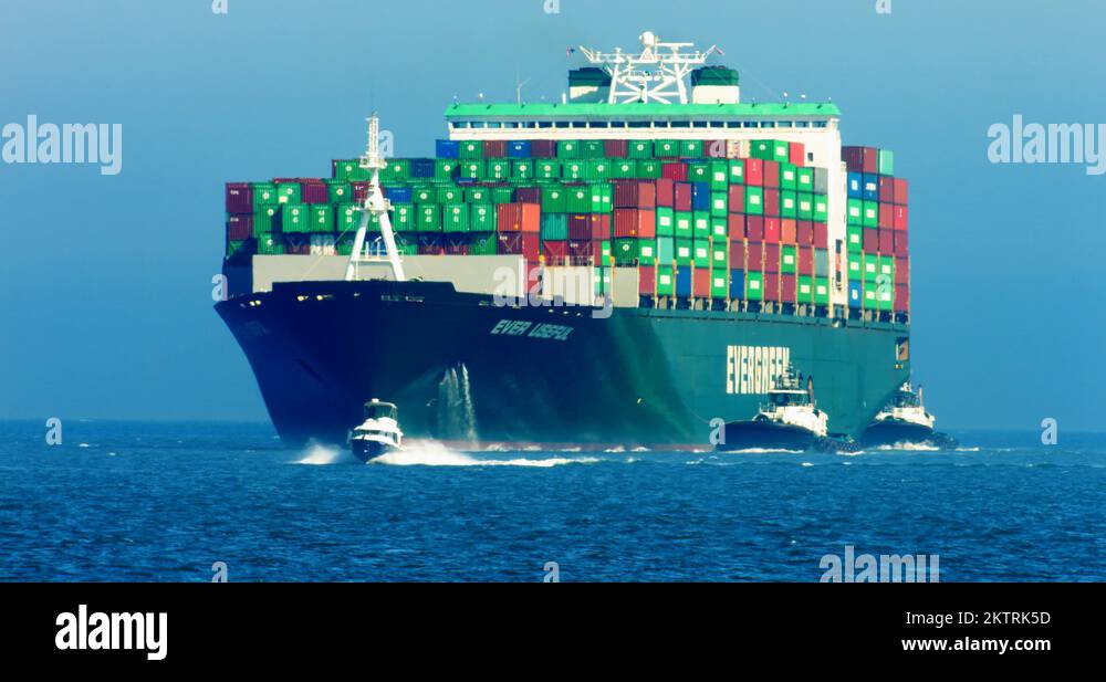 Cargo container ship and pusher tugs enter the sea port during the heat ...