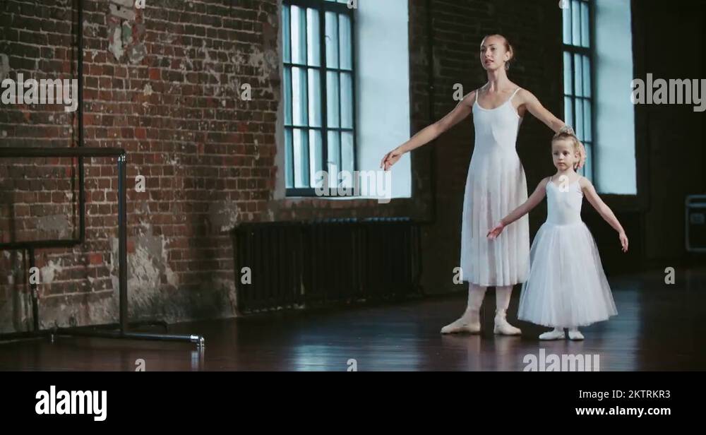 adult ballerina teaching a little girl, classical ballet in the loft ...