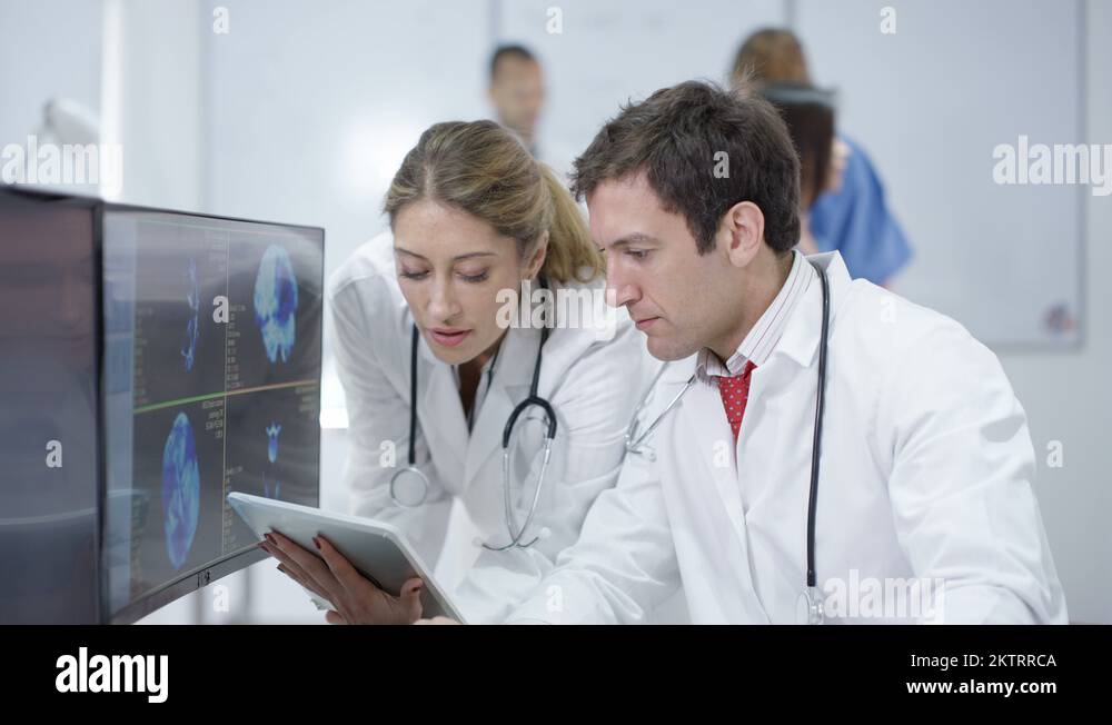 4K Medical team in modern clinic looking at patient scans on computer ...