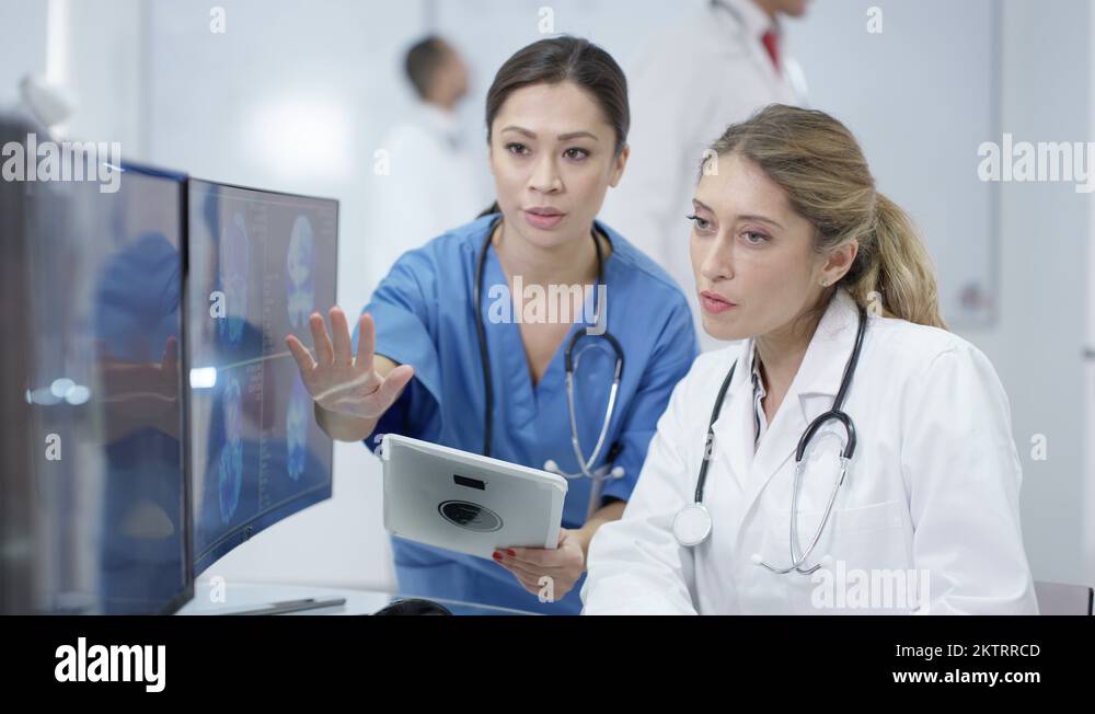 4K Medical team in modern clinic looking at patient scans on computer ...