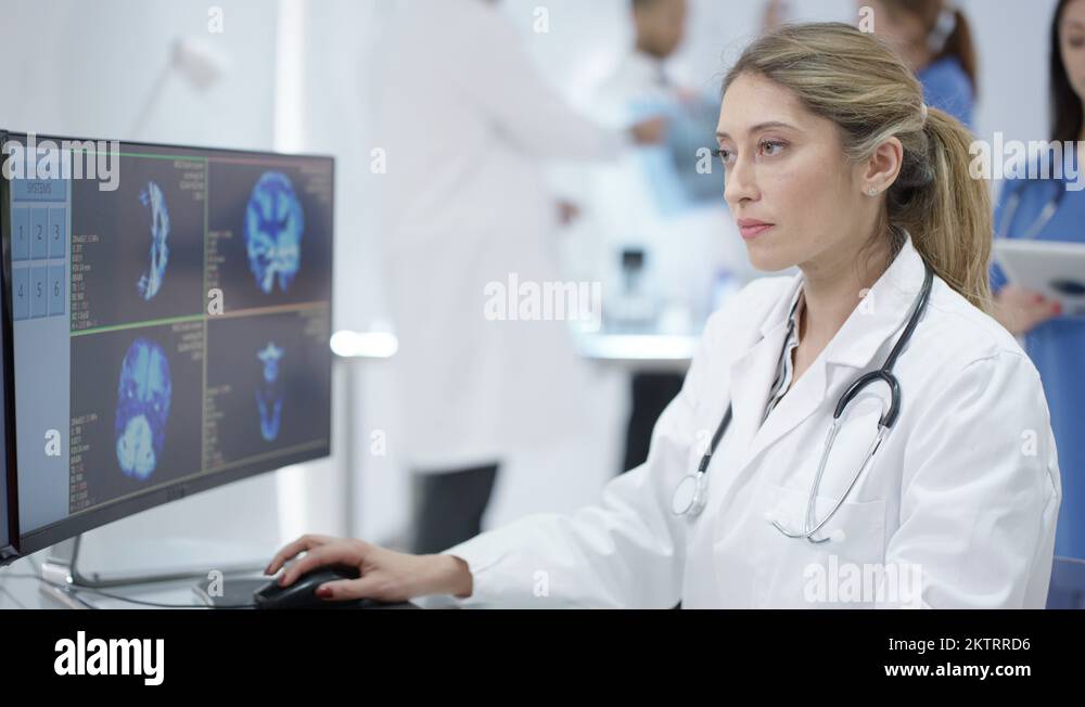 4K Medical team in modern clinic looking at patient scans on computer ...