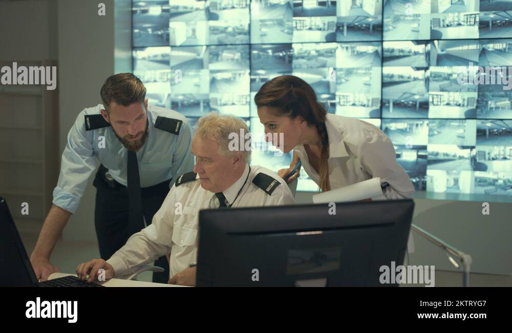 4K Security staff watching screens & discussing in observation control ...