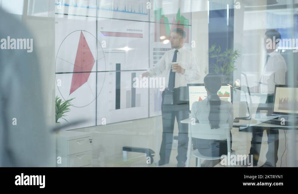 4K Business team in modern office, looking at video wall with graphs ...