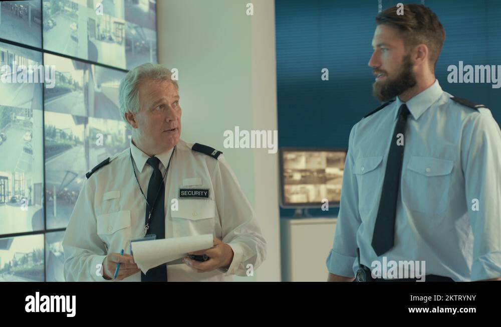 4K Security staff watching screens & discussing in observation control ...