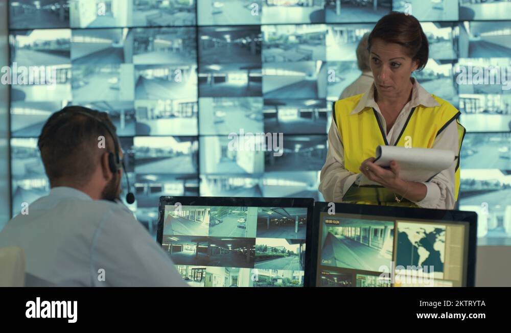 4K Security staff watching screens & discussing in observation control ...