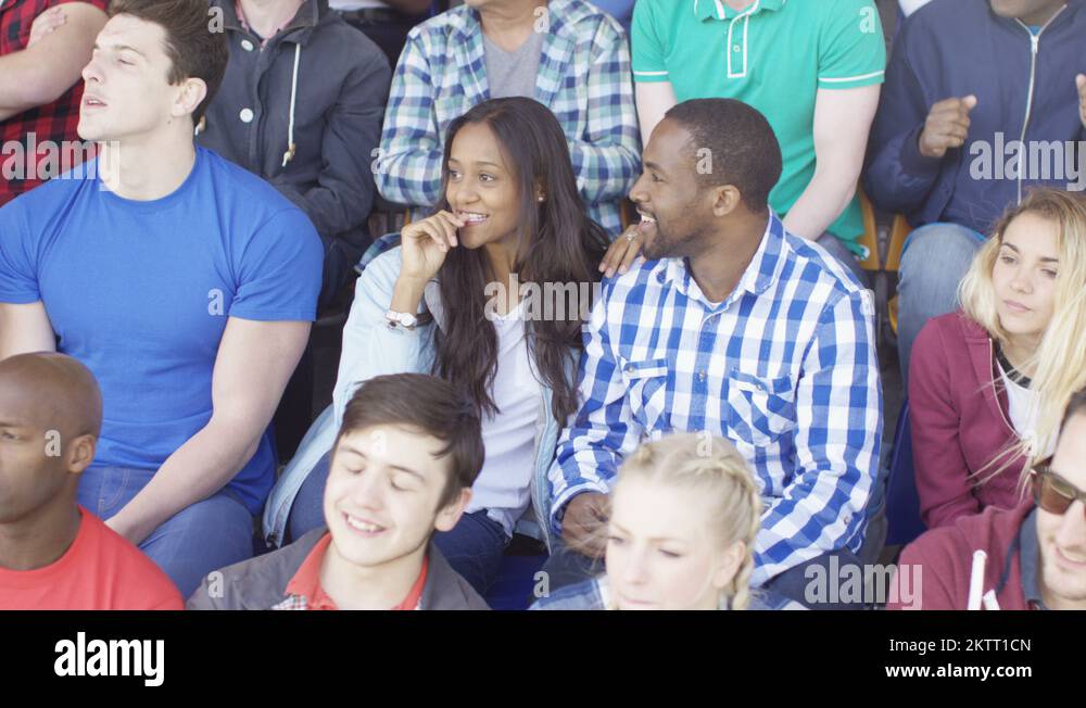 4K Crowd cheering on their team at sports event, focus on young couple ...