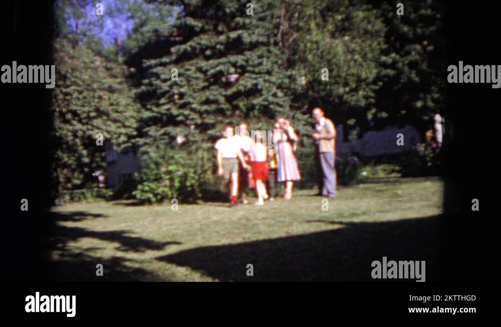 1964: adults and children assembling in front of tall pine trees and ...