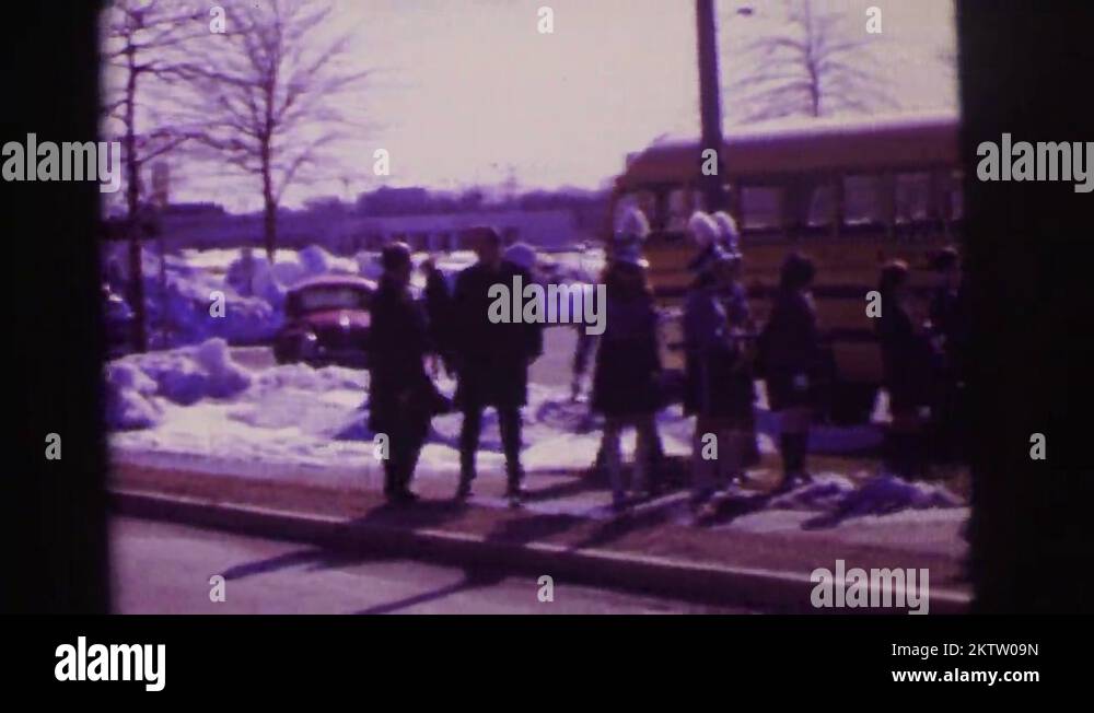 1974: children waiting at bus stop in cold winter snow weather LYNBROOK ...