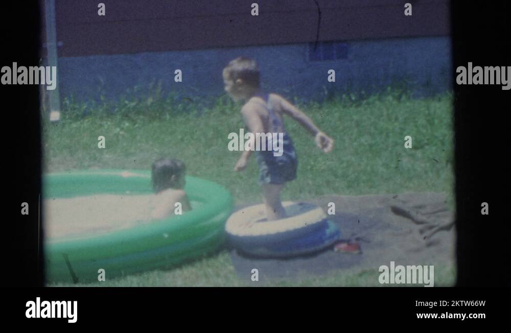 1964: two children playing in an inflatable pool in the yard of a house ...