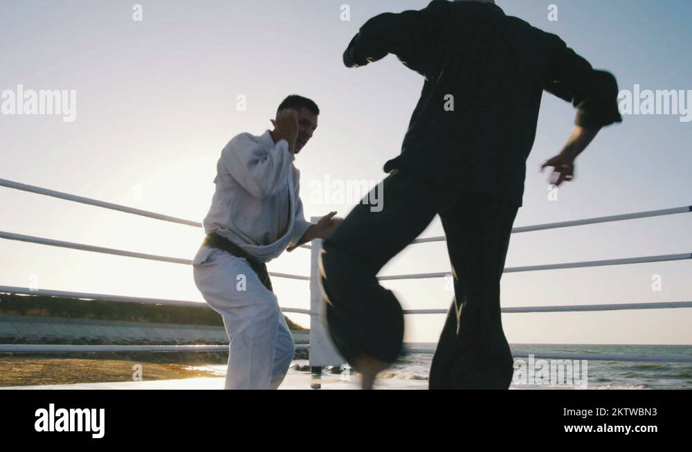 Two professional karate fighters are fighting on the beach boxing ring ...