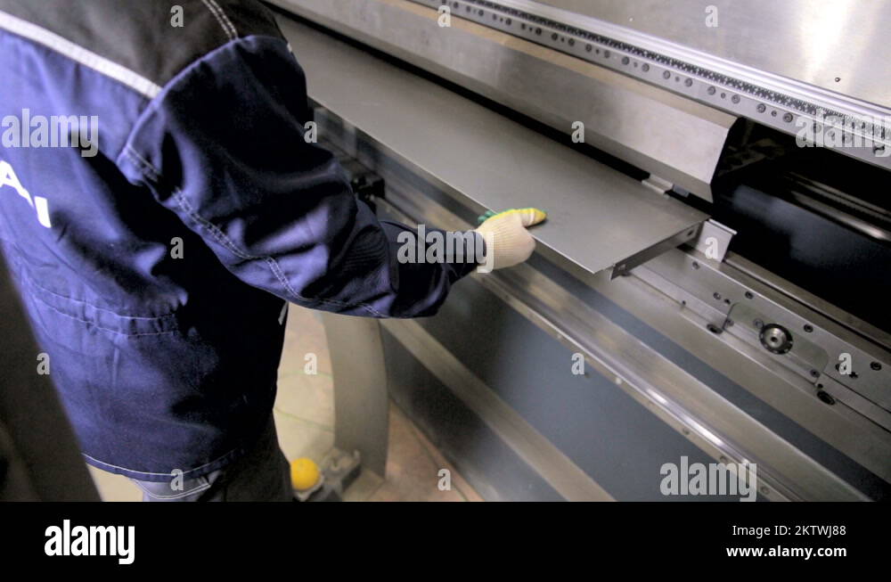 Worker hands bend metal sheet on a modern bending industrial machine at ...