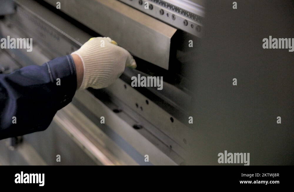 Worker hands bend metal sheet on a modern bending industrial machine at ...