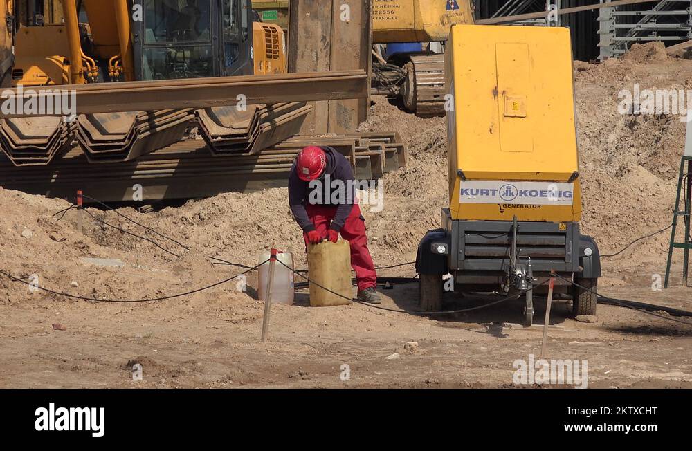 Worker man pouring diesel fuel into generator and highway constructing ...