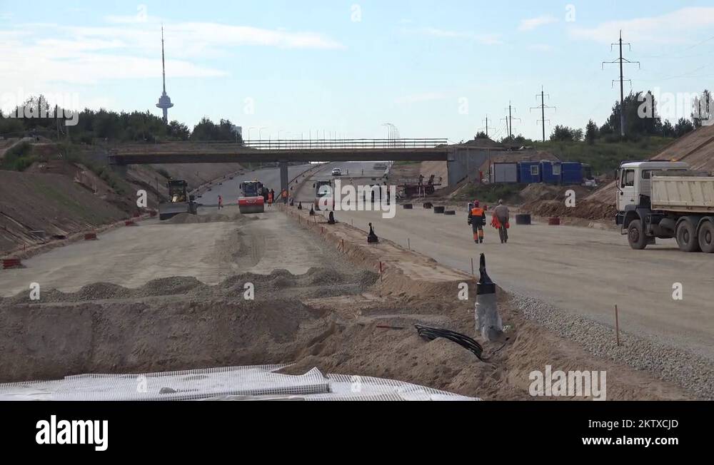 Excavator digging sand and roller machine leveling new highway layers ...