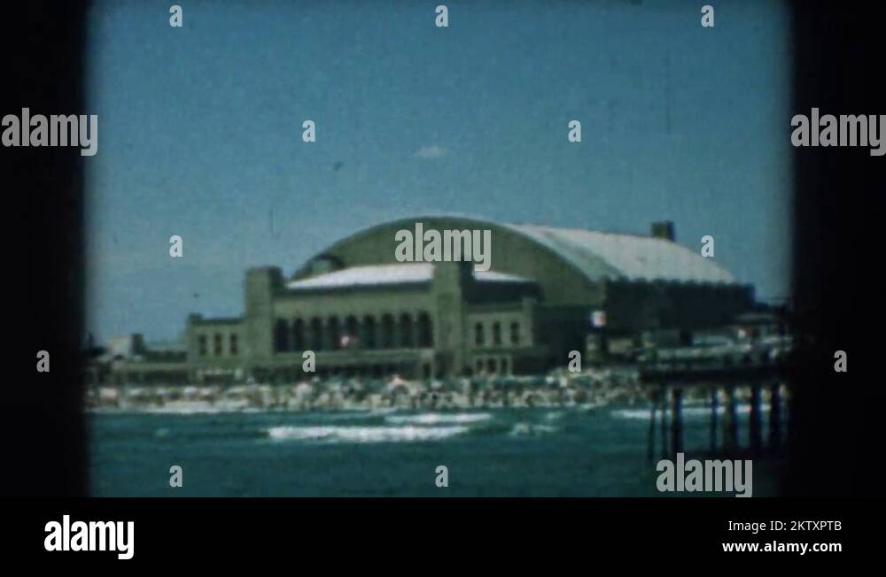 1958: a coastal city has large buildings, semicircular roofed arena ...