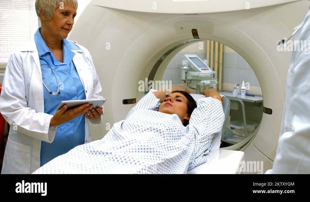 Doctor reviewing chart of female patient on digital tablet before mri ...