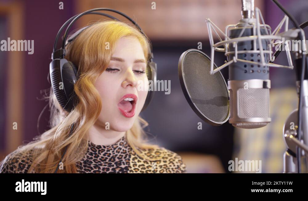 4K Portrait smiling female vocalist in recording studio singing into ...