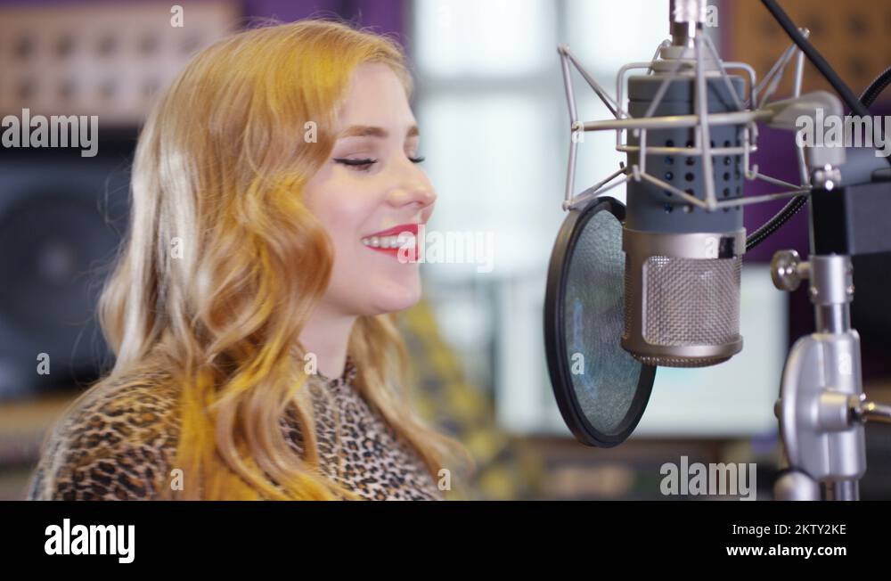 4K Portrait smiling female vocalist in recording studio singing into ...