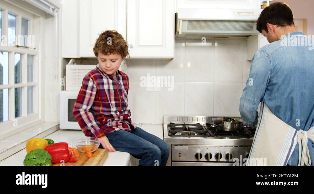 Boy helping father while cooking food in kitchen Stock Video Footage ...