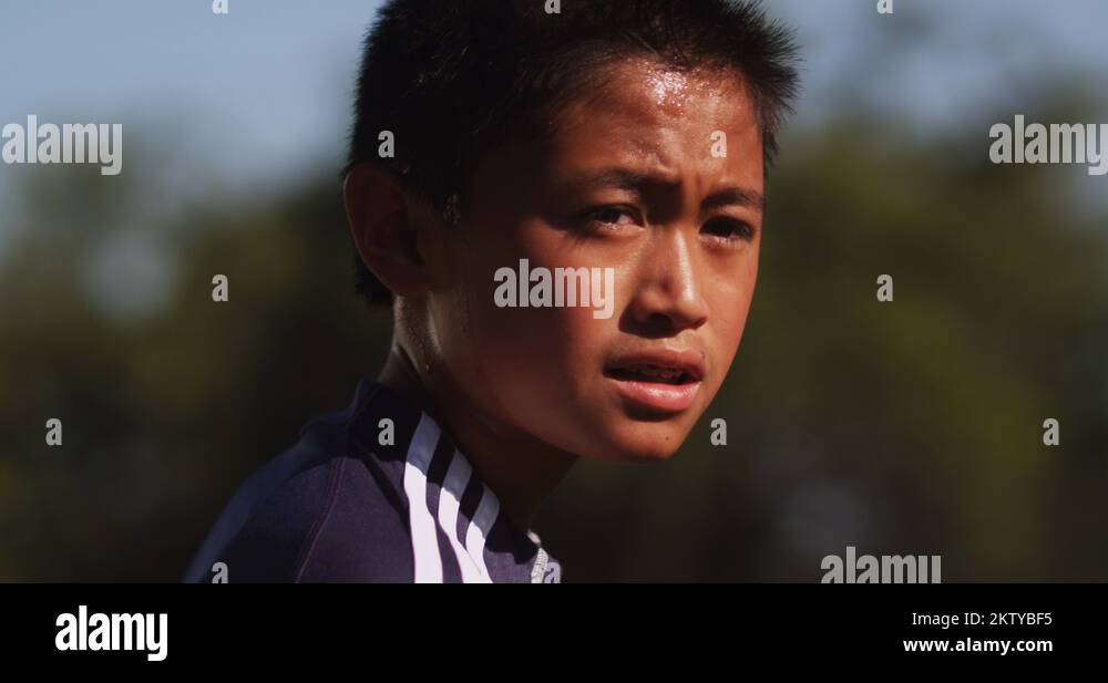 A boy soccer player running down the field with sweat dripping off his ...