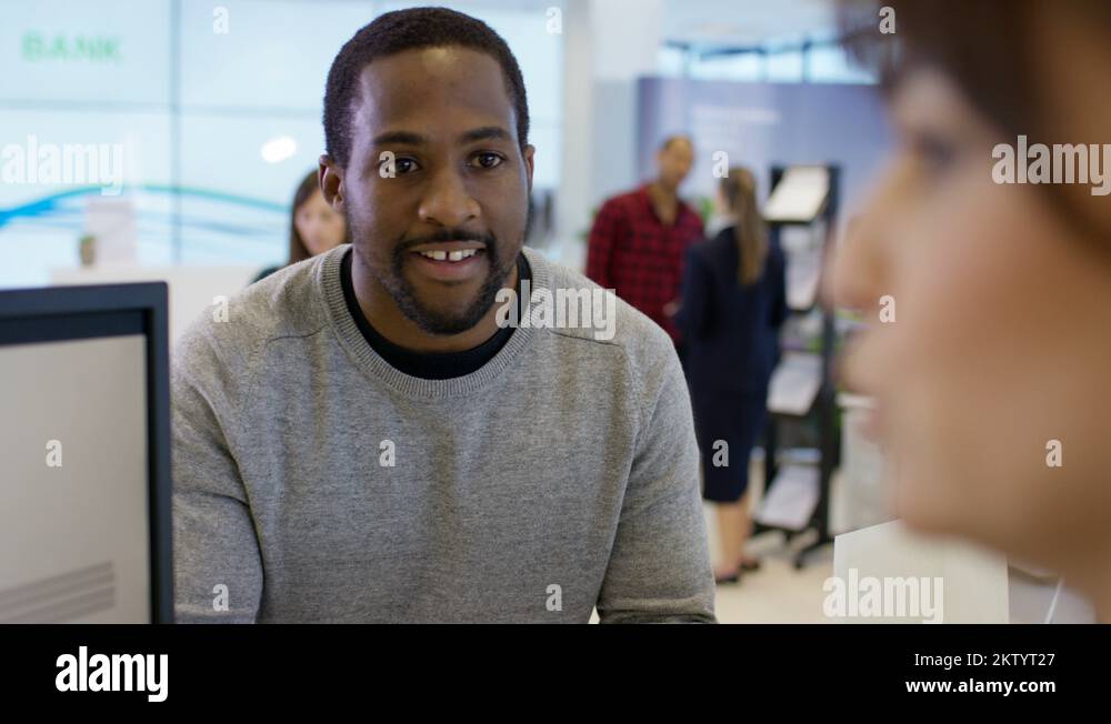 4K Worker at customer service desk assisting customer in modern bank ...