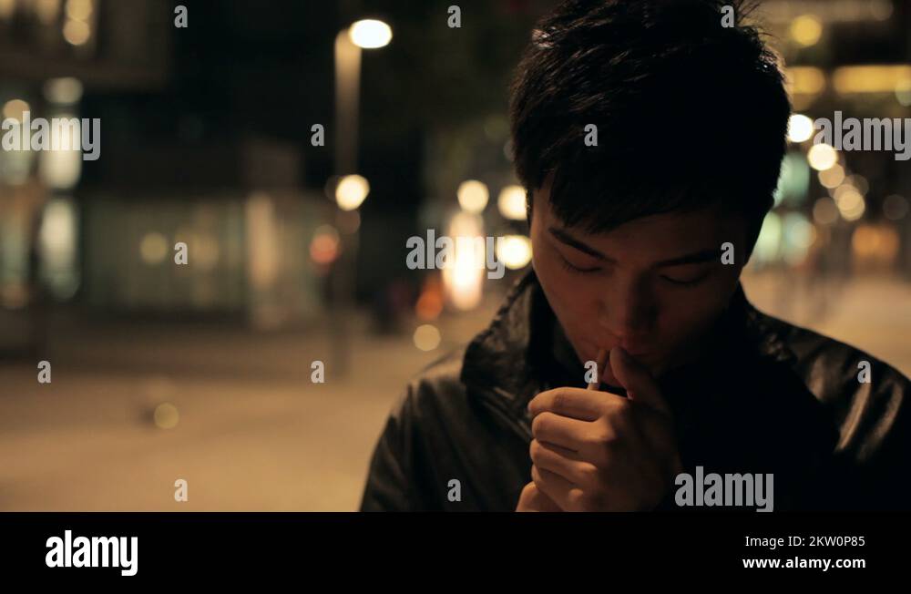 CU Young man walking and smoking cigarette on street at night / China ...