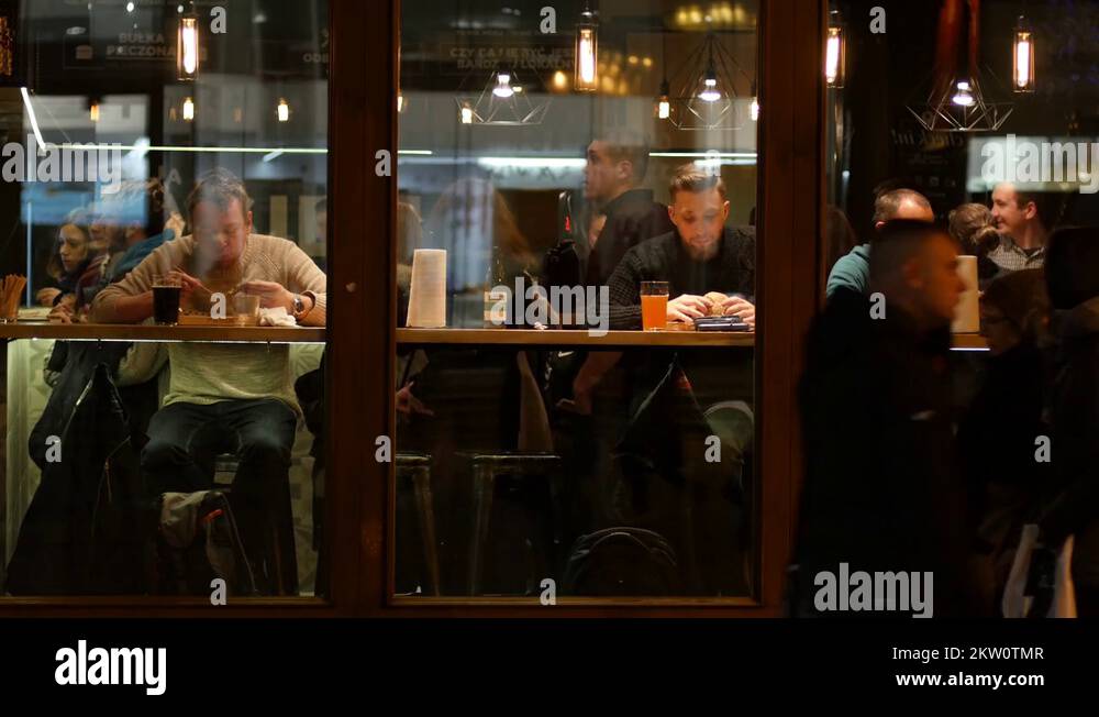 People sitting eating food chicken and burgers behind glass restaurant ...