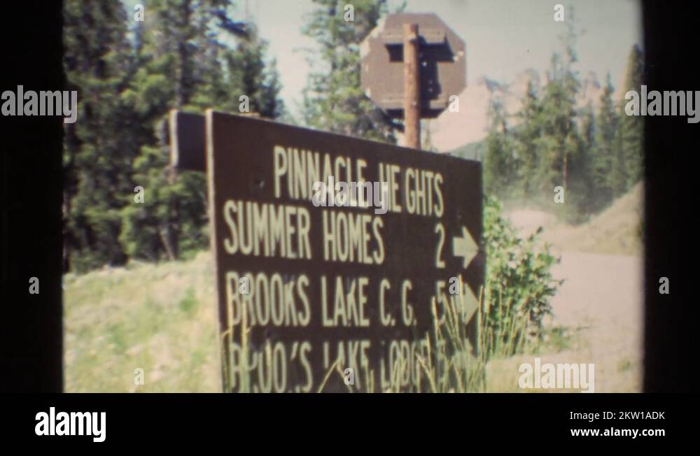 1980: sign posted along road lists locations with arrows in a forest ...