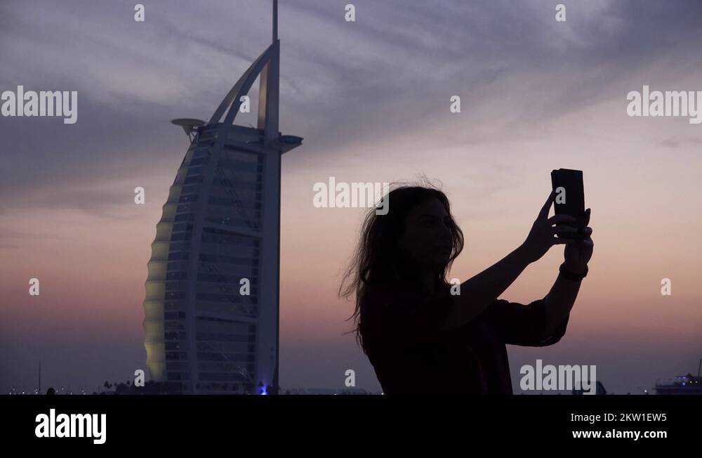 Dusk sunset time in Dubai girl taking selfie photo to Burj al Arab icon ...