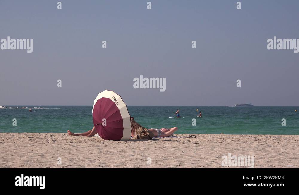 Dubai beach 4K girls under sun umbrella sunbath on ocean coast ...