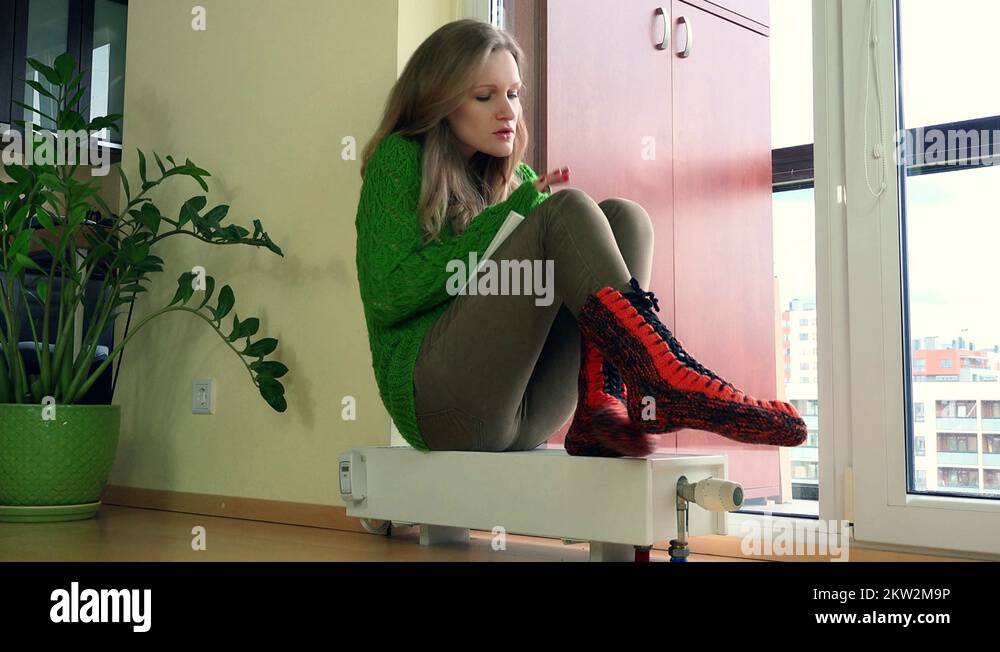 Frozen Woman Reading Book Sitting On Radiator And Adjusting Thermostat ...