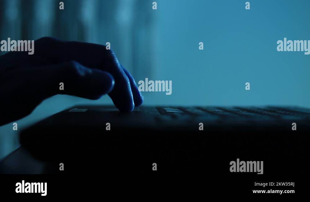 Silhouette of male hand typing on a laptop keyboard in the darkness ...