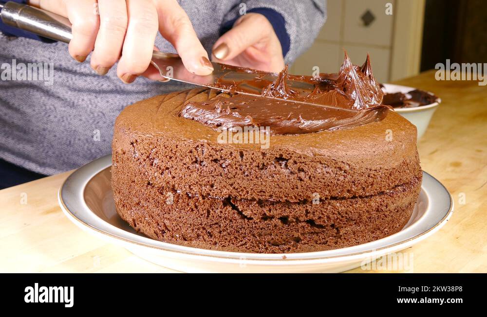 Woman adding topping to a chocolate sponge cake Stock Video Footage - Alamy
