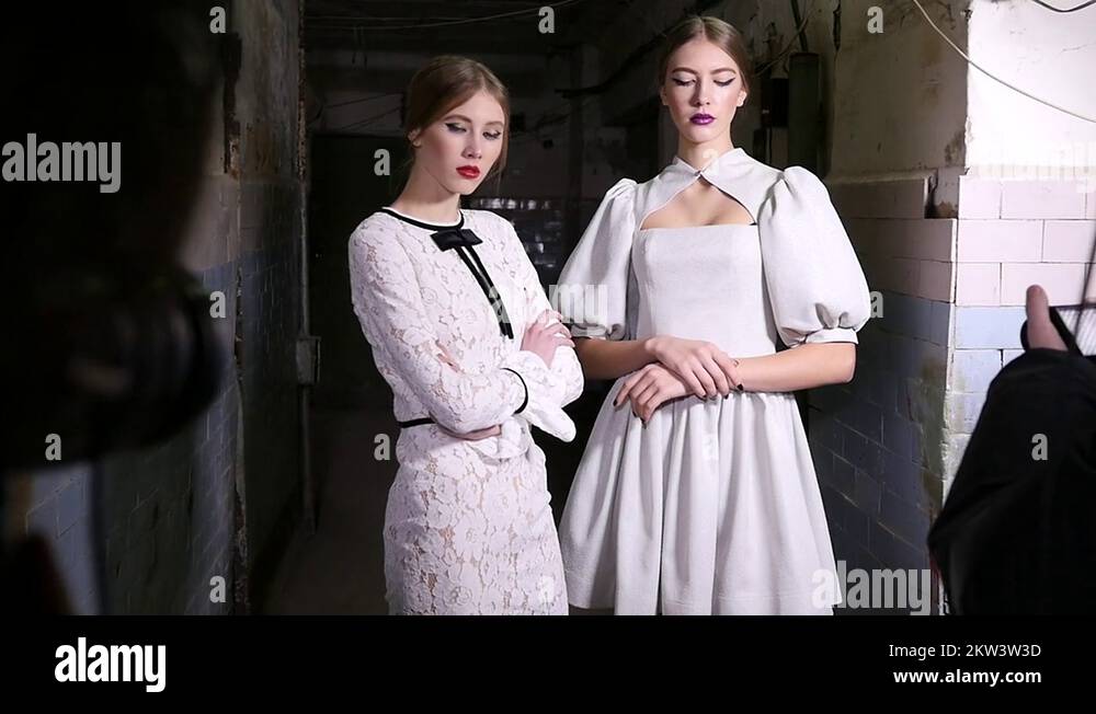 Two slim young girls models stay posing during photo session backstage ...