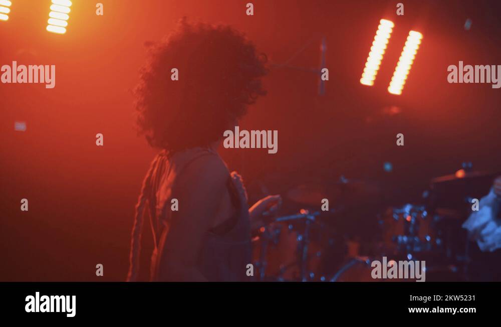 Girl in afro wig and noose around neck dance on scene, moving colorful ...