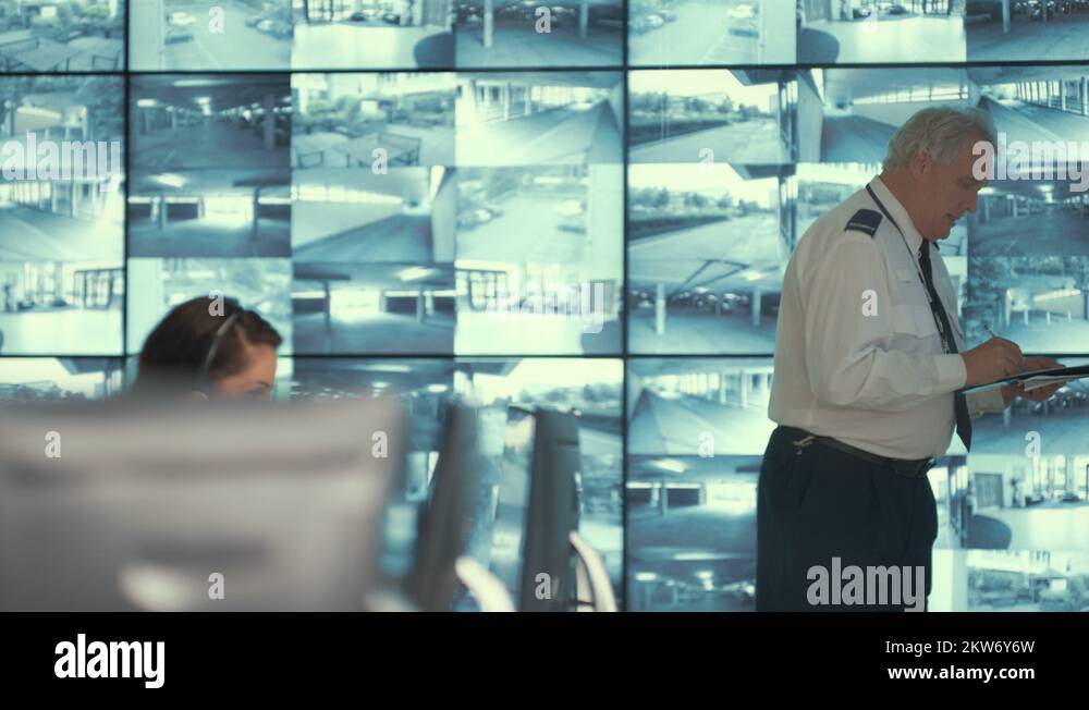 4K Security staff watching screens & discussing in observation control ...