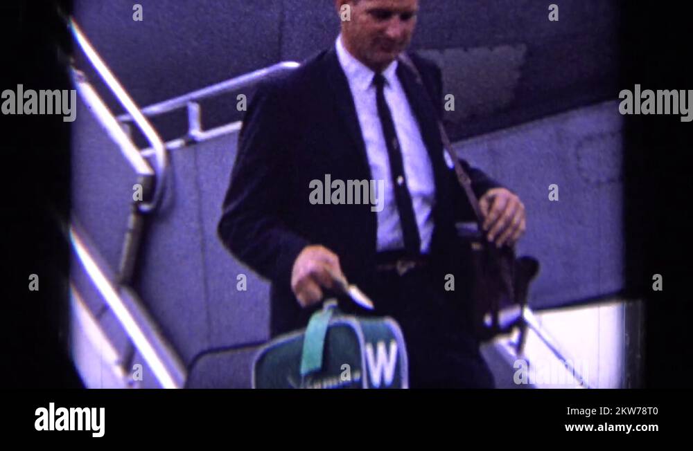 1963: men in black suit coming down stairs from airliner while carrying ...