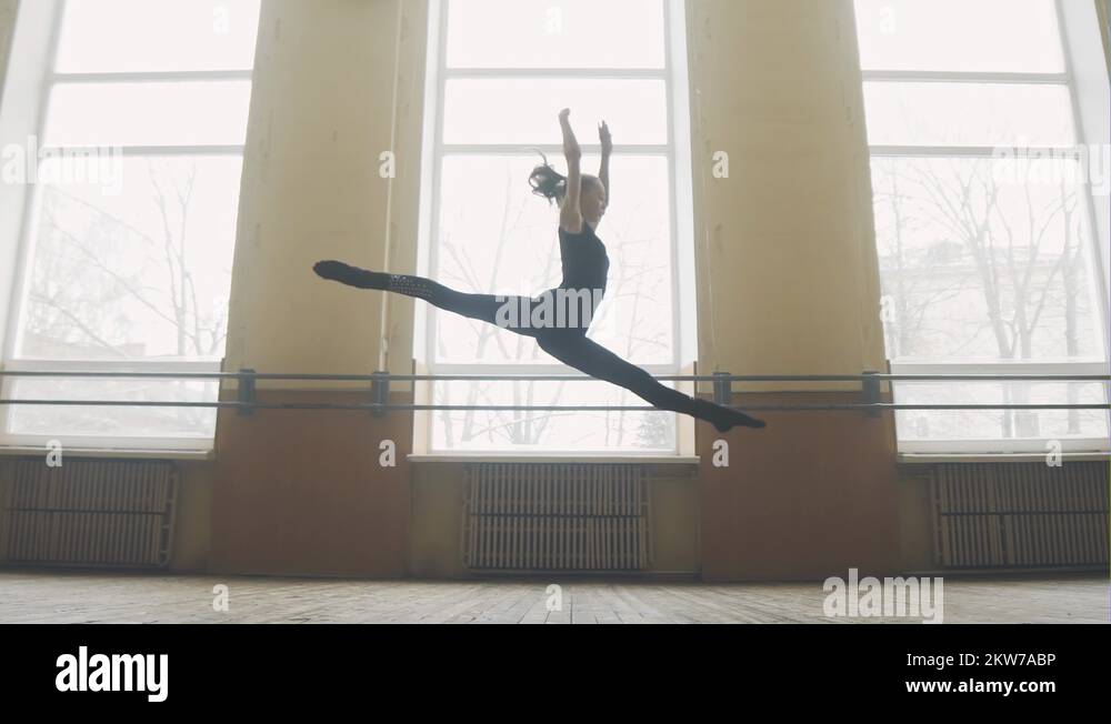 Modern style dancer performing splits in the air, jété in a large ...