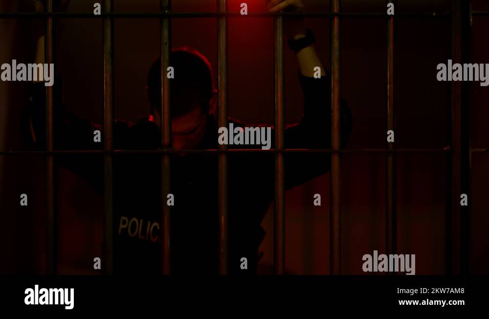 Police officer sad behind bars in jail Stock Video Footage - Alamy