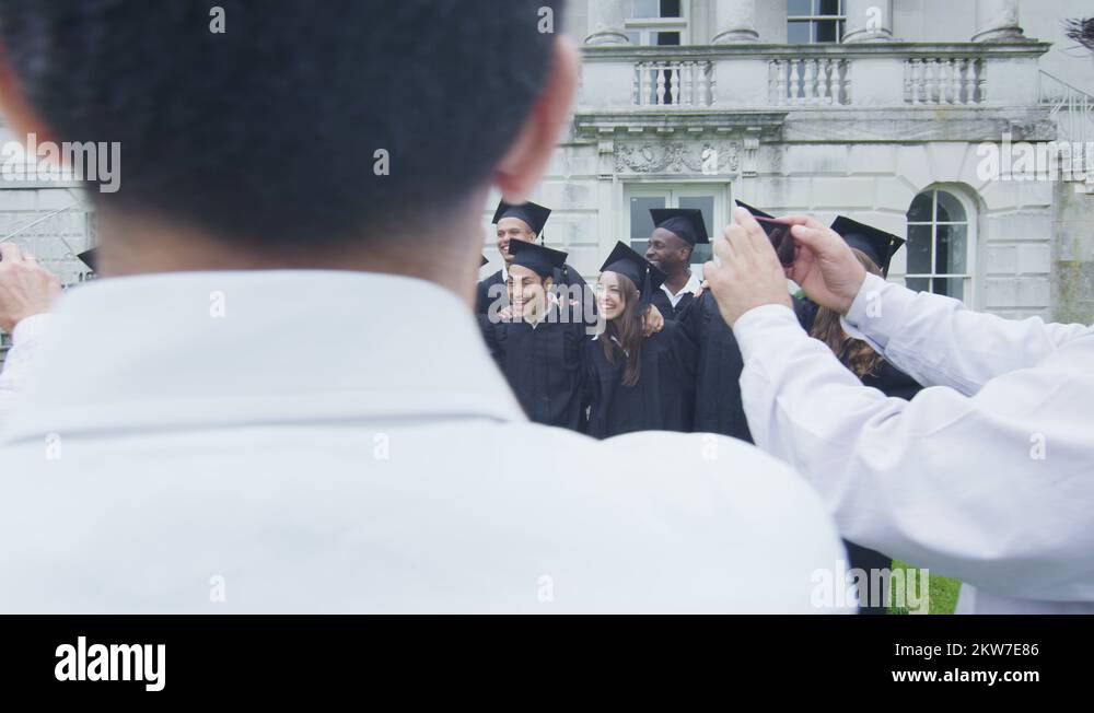 4K Happy students on graduation day posing for photos outside college ...