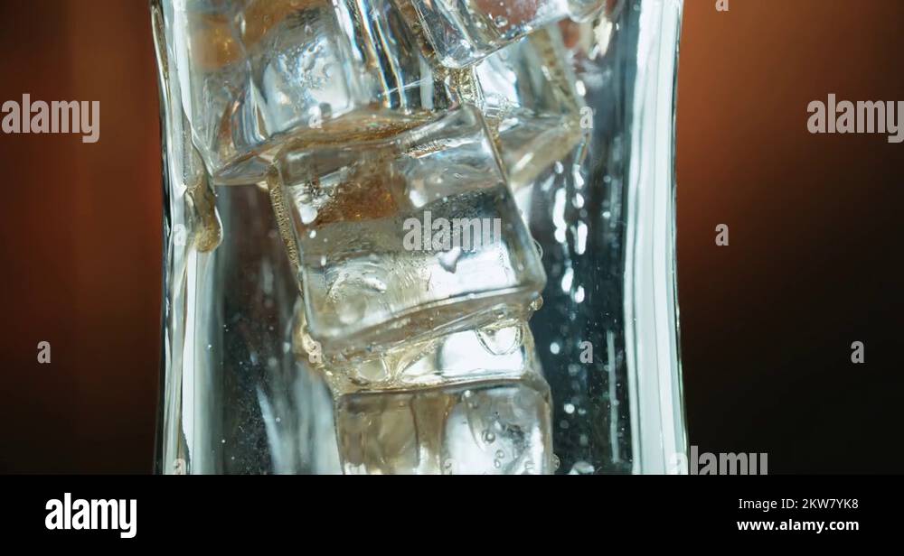 Cola with ice. Pouring Cola with Ice cubes and bubbles in big glass ...