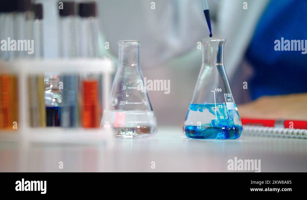 Dripping chemical liquid in glass flask. Chemical reaction in lab flask ...