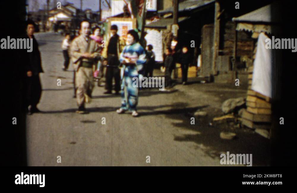 1952: two japanese women in traditional costume walk down a busy street ...