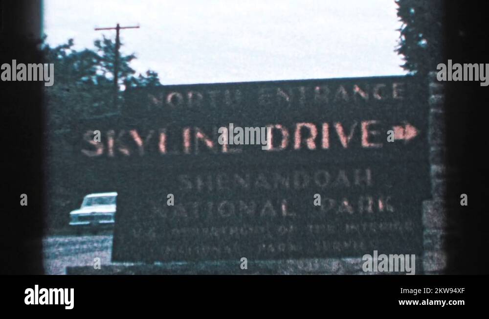 1964: a sign board represents skyline drive and a car moving backside ...