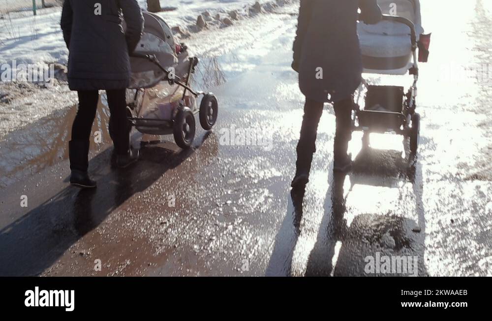 Camera chases two women with strollers that walk in dirty but sunny ...