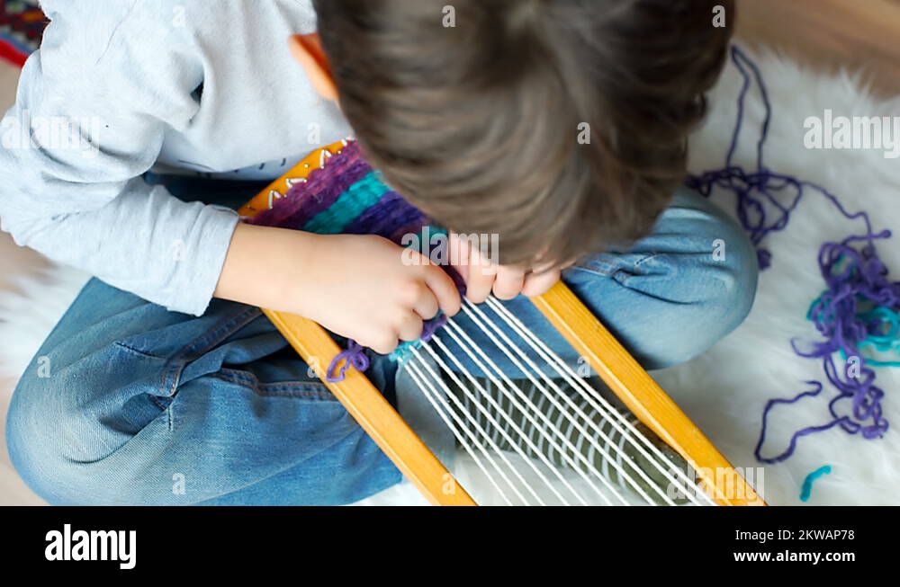 Boy sitting with his legs crossed and weaving something on loom Stock ...